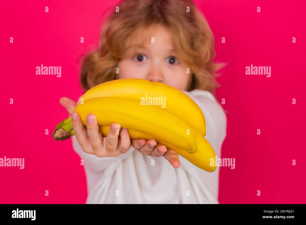 Child hold banana in studio. Studio portrait of cute kid boy with ...