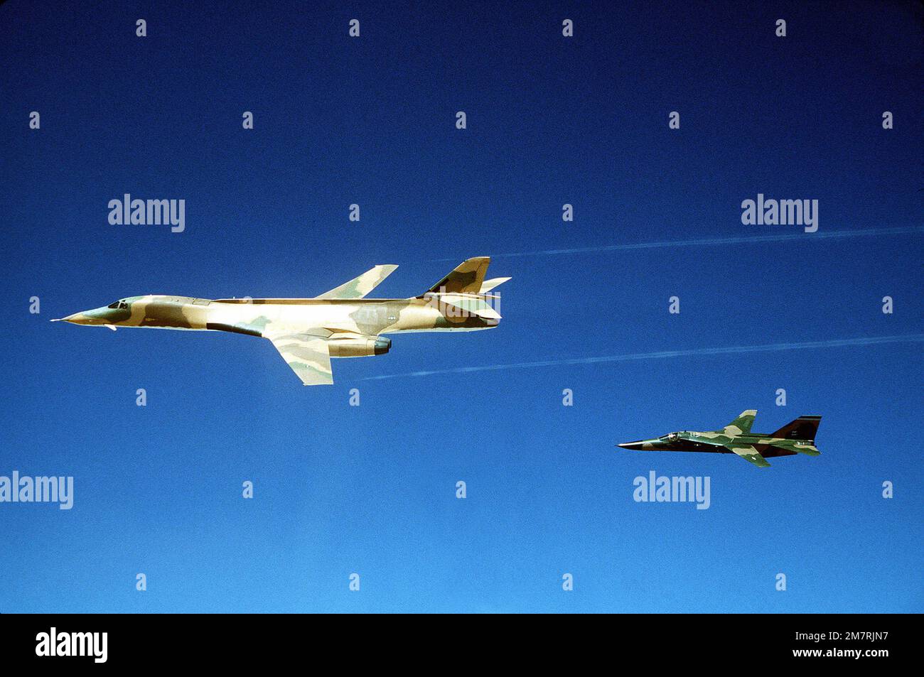 A left side view of a B-1 bomber aircraft, being followed by an FB-111 ...