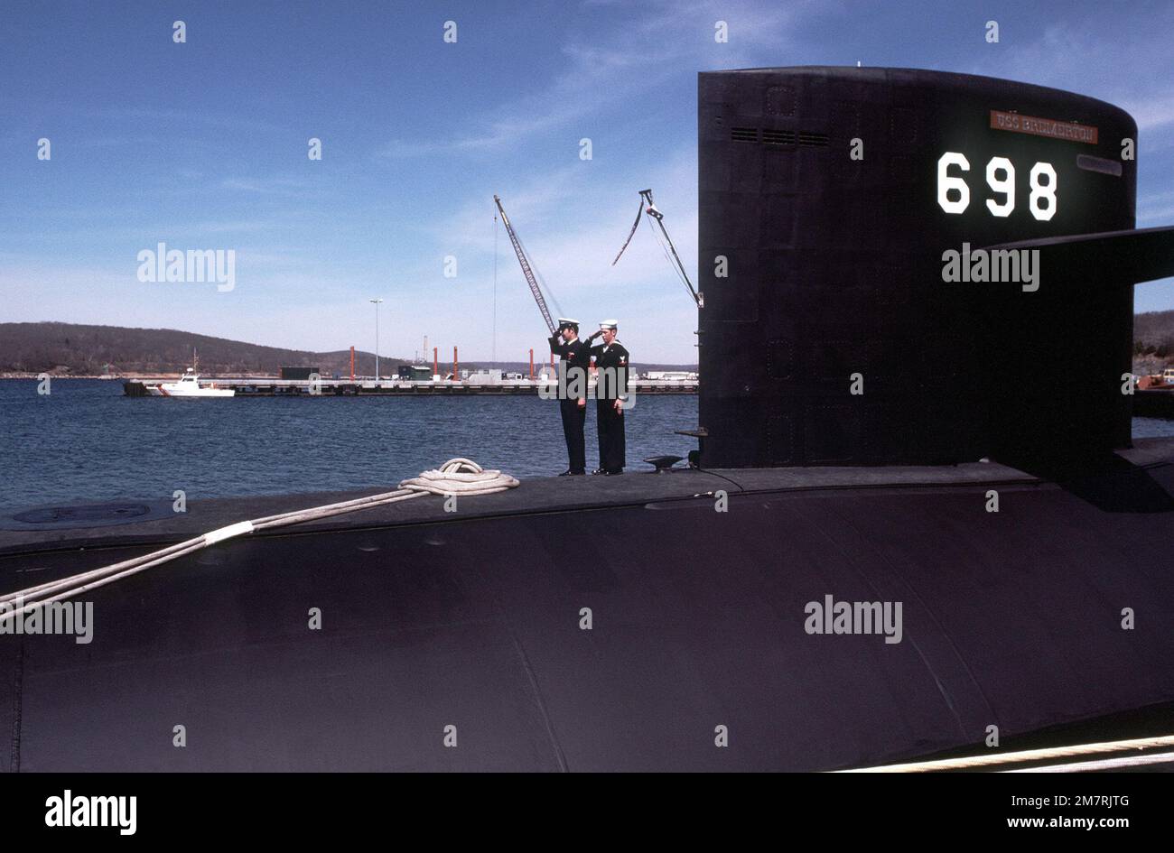 Two crewmen salute after colors are raised aboard the nuclear-powered ...
