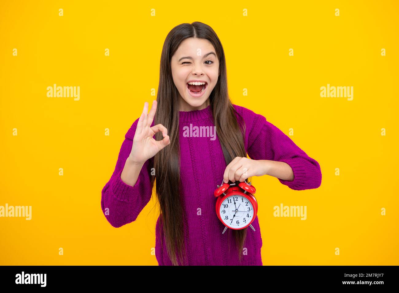 Excited face. Teen student girl hold clock isolated on yellow ...