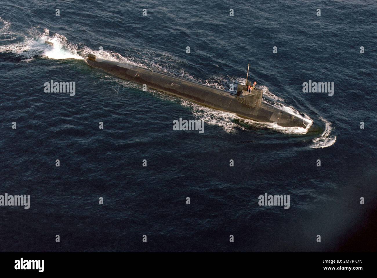 A starboard bow view of a nuclear-powered submarine underway. Base ...