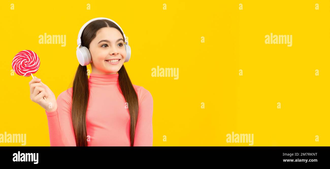 happy child listen music in headphones with lollypop on yellow ...