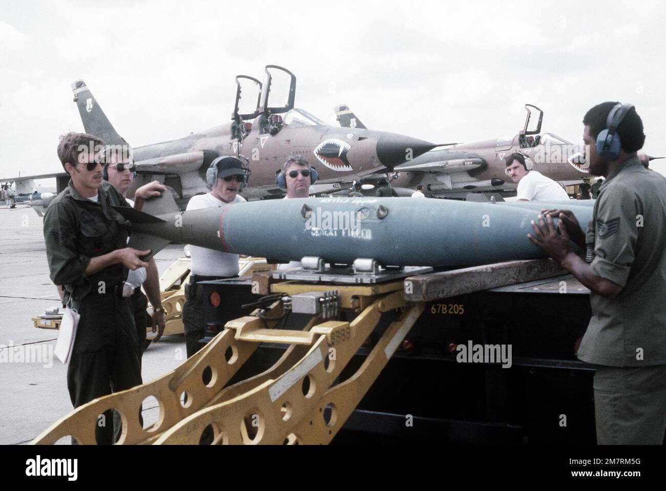 A crew places a 500-lb Mark 82 bomb, which will be loaded on an F-105 ...