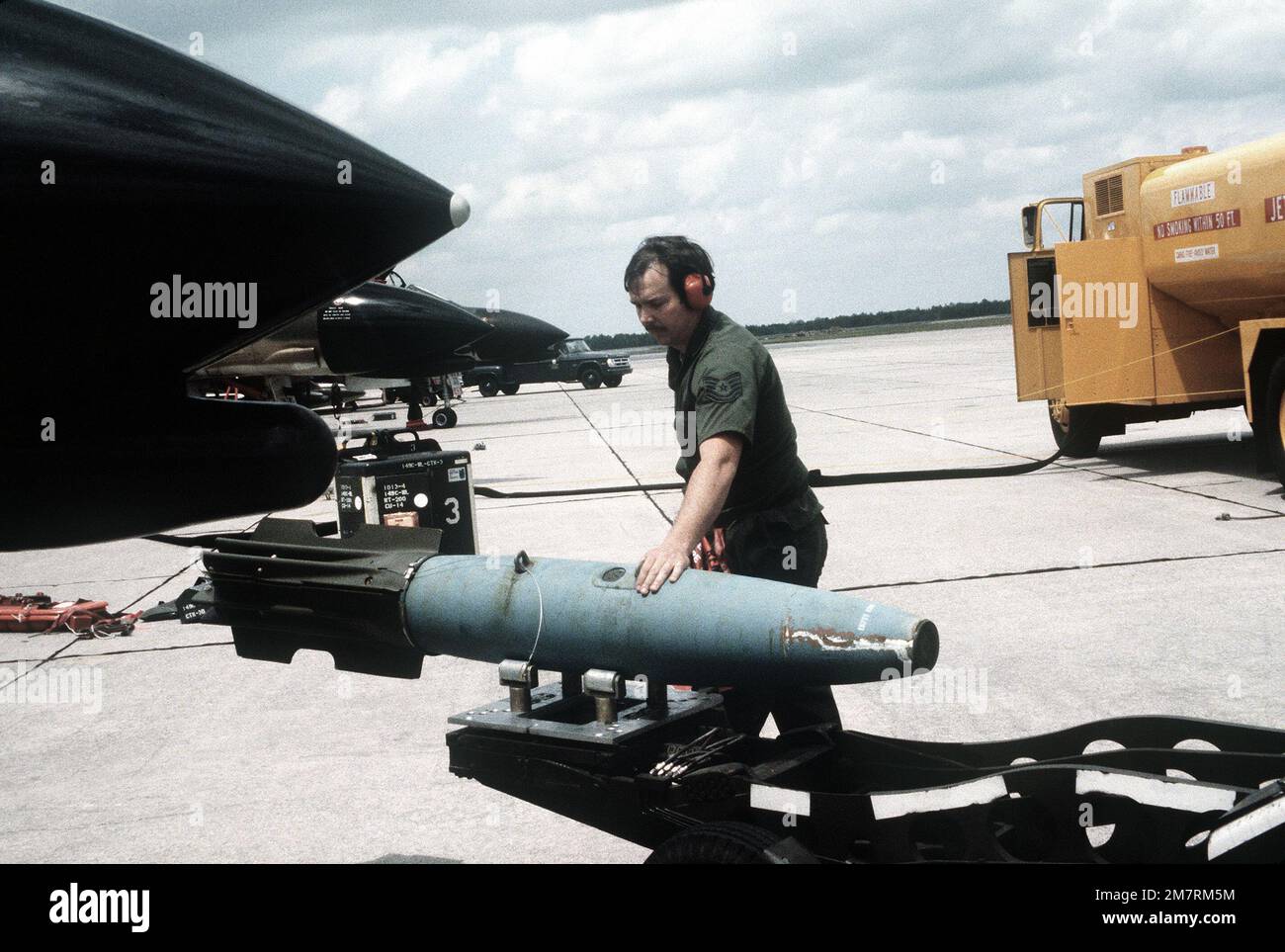AN airman walks beside a 500-lb. Mark 82 hi-drag bomb, being carried to ...