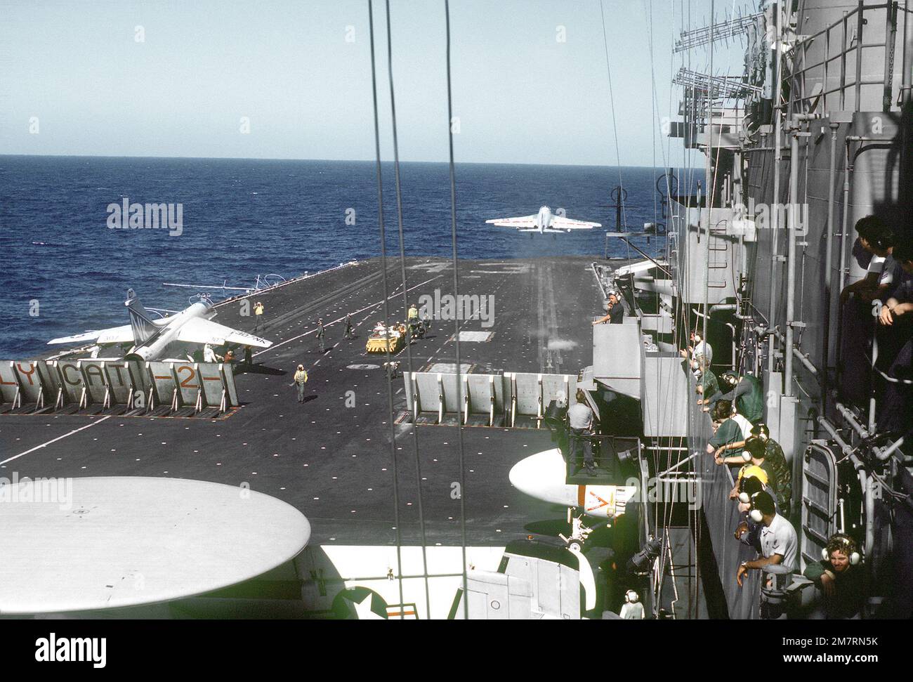 A rear view of an F-4 Phantom II aircraft being launched and an A-7 ...