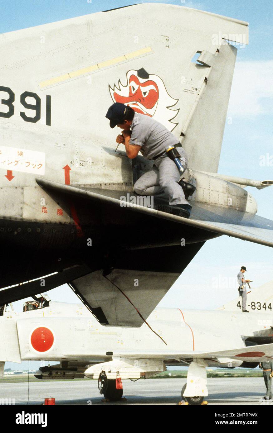 A crewman from the Japanese Air SelF Defense Force does maintenance on ...