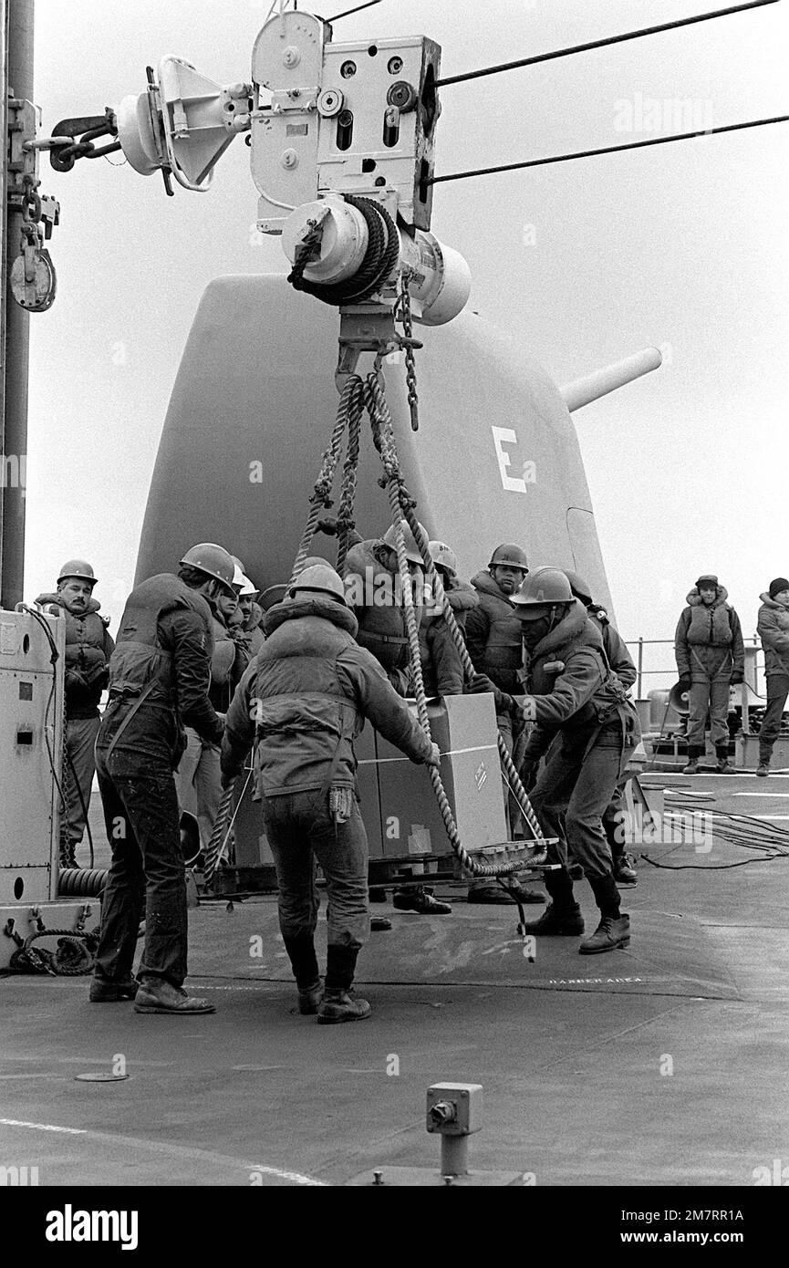 Crewmen aboard the destroyer USS NICHOLSON (DD-982) lower a box of ...
