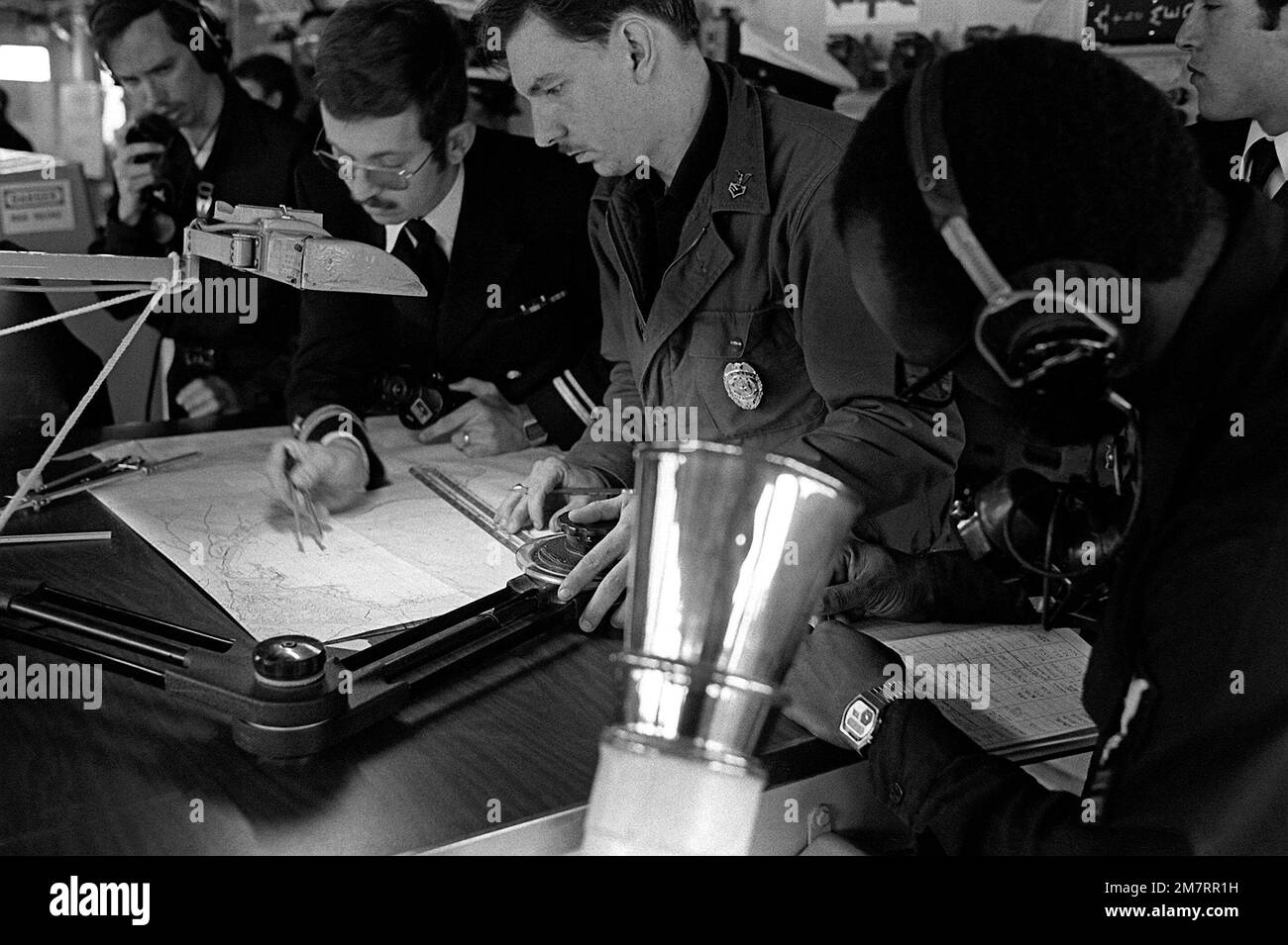 Crewmen aboard the destroyer USS JOHN HANCOCK (DD-981) plot the ship's ...