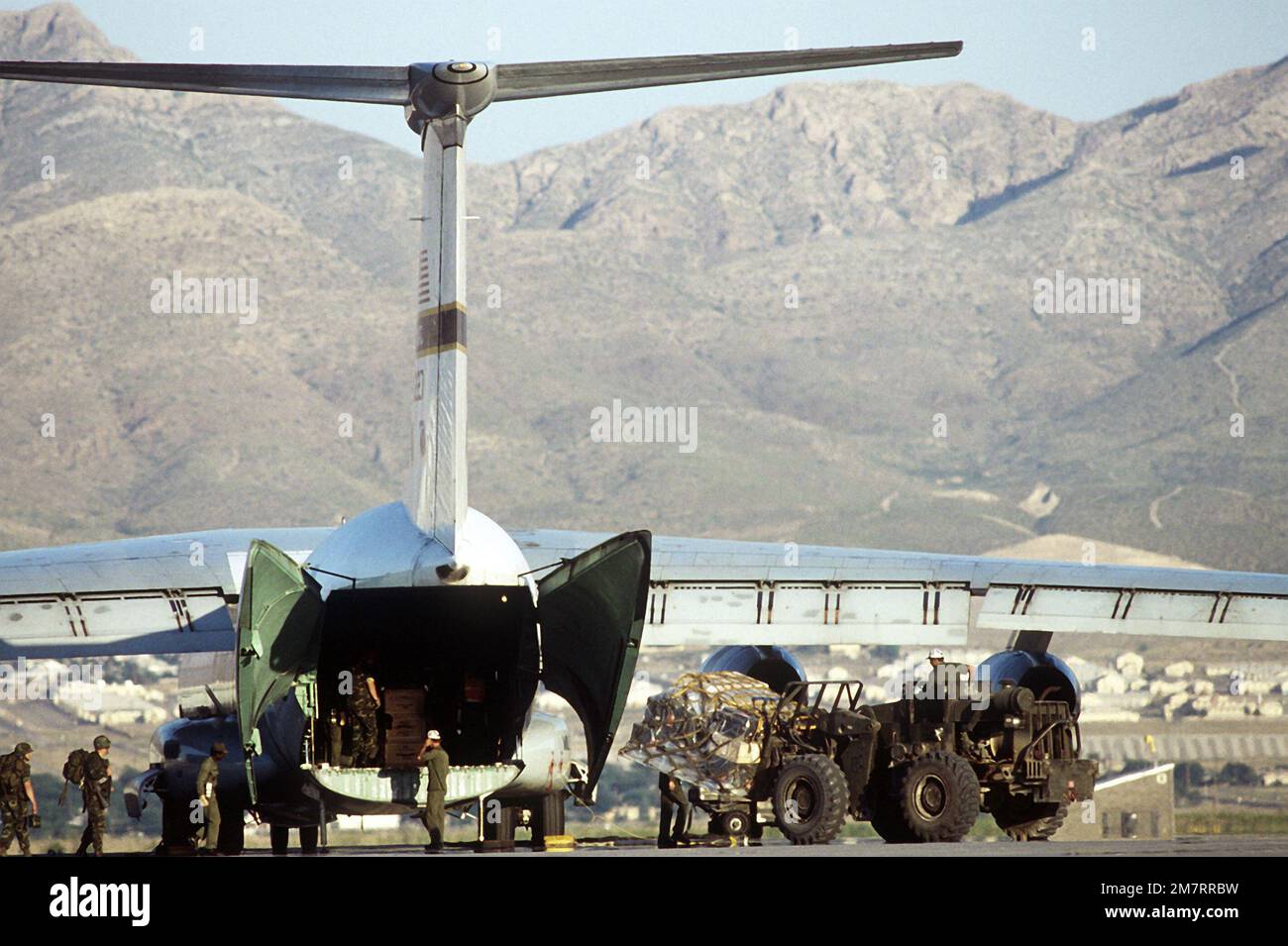 Airmen unload equipment from a C-141 Starlifter aircraft with the aid ...