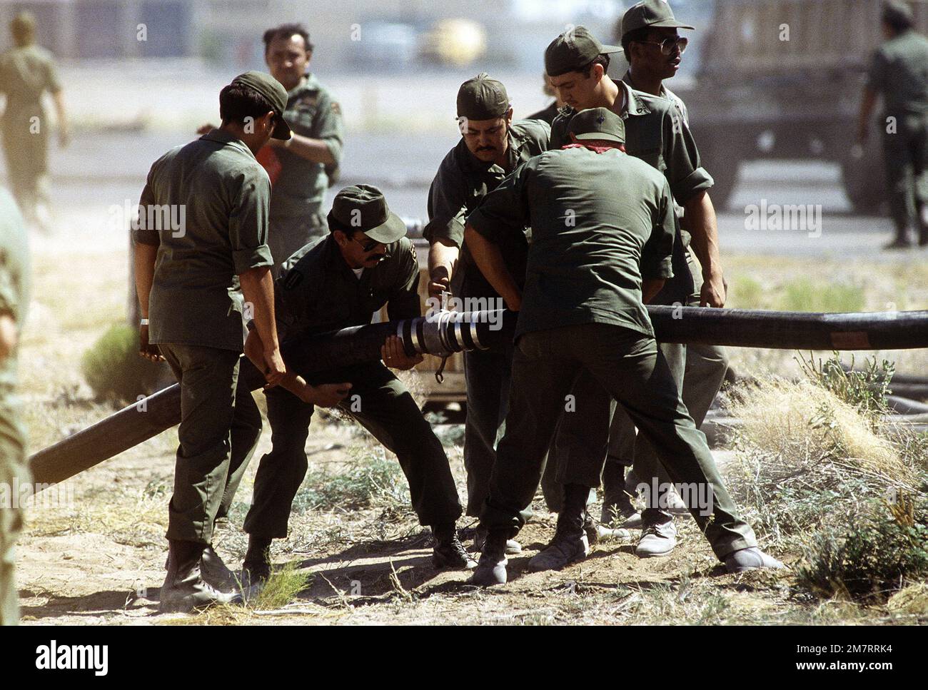 Airmen building a hot-bladder pit refueling site assemble a fuel hose ...