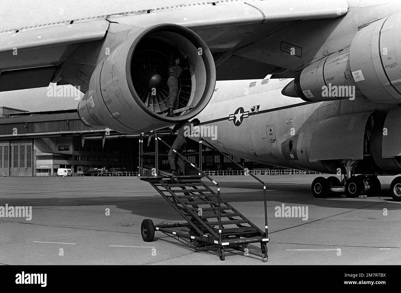 Ground crew members check the engine intake of a C-5A Galaxy aircraft ...