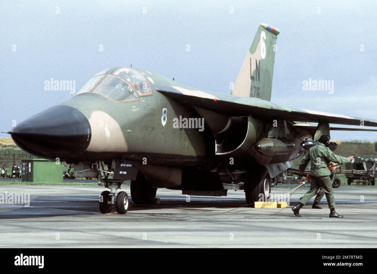 A view of an F-111 aircraft set for takeoff as ground crew members ...