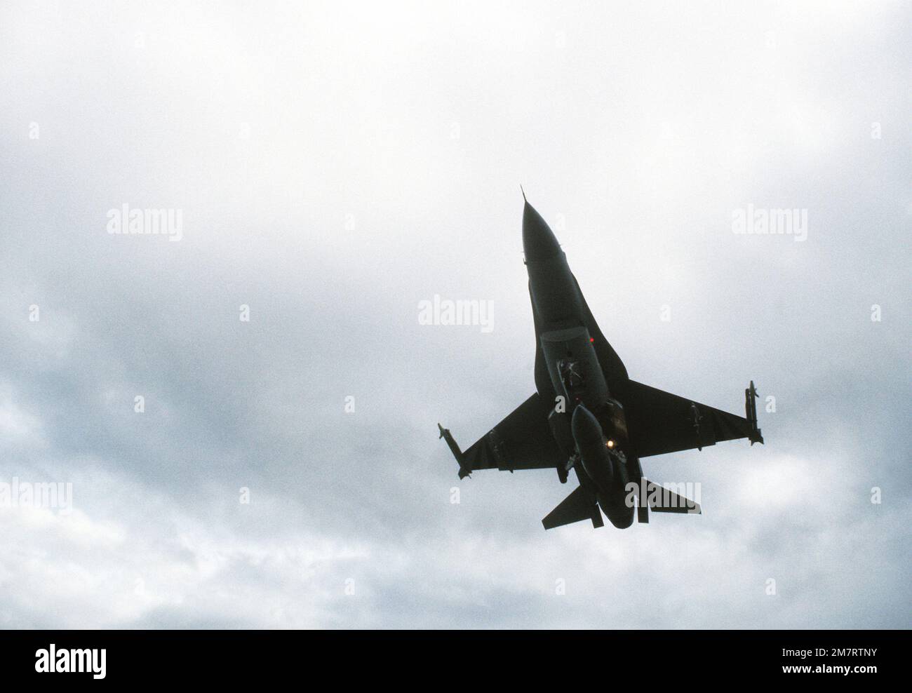 Bottom view of an F-16 Fighting Falcon aircraft silhouetted against ...