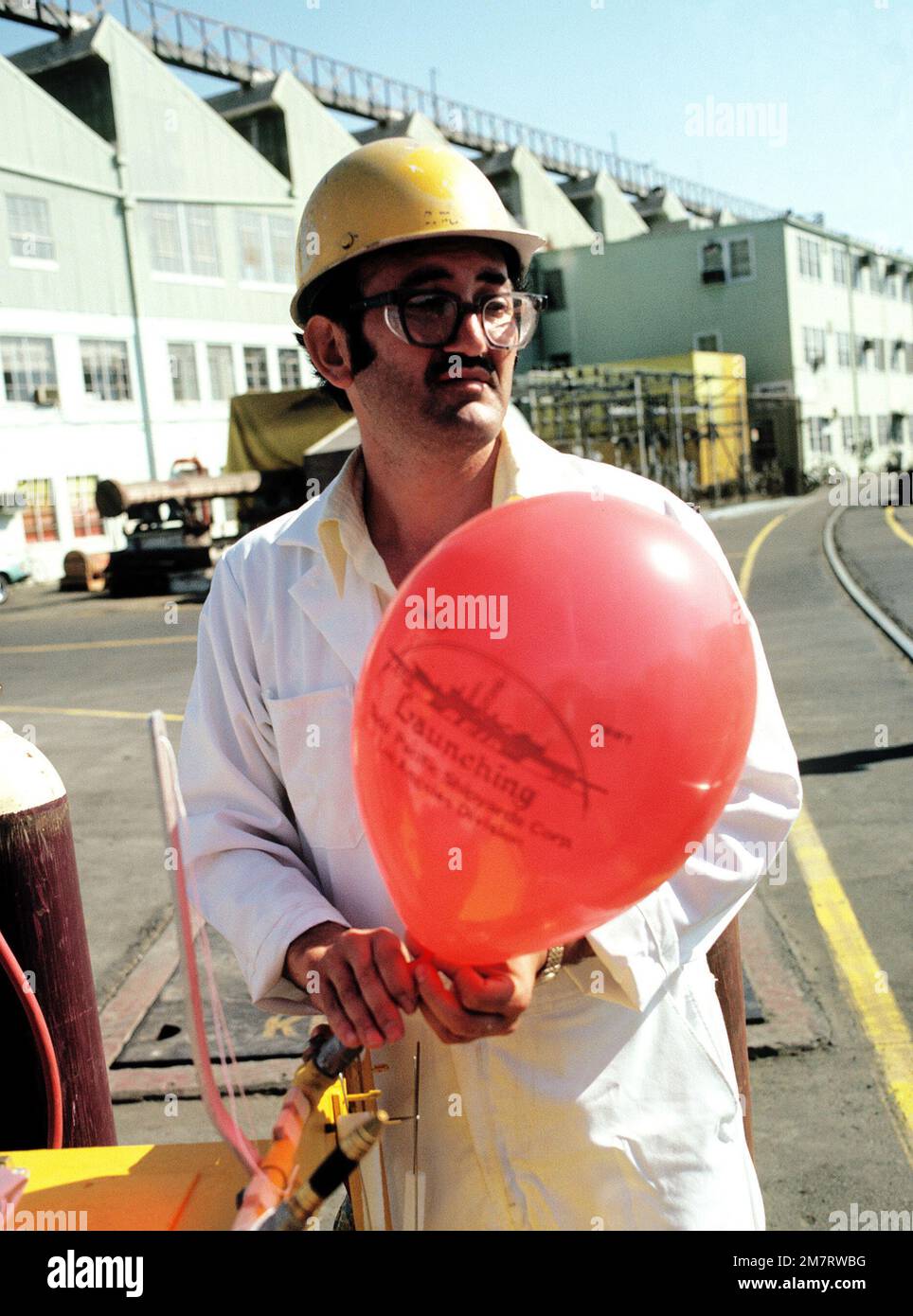A shipyard worker inflates a balloon with helium in preparation for the ...
