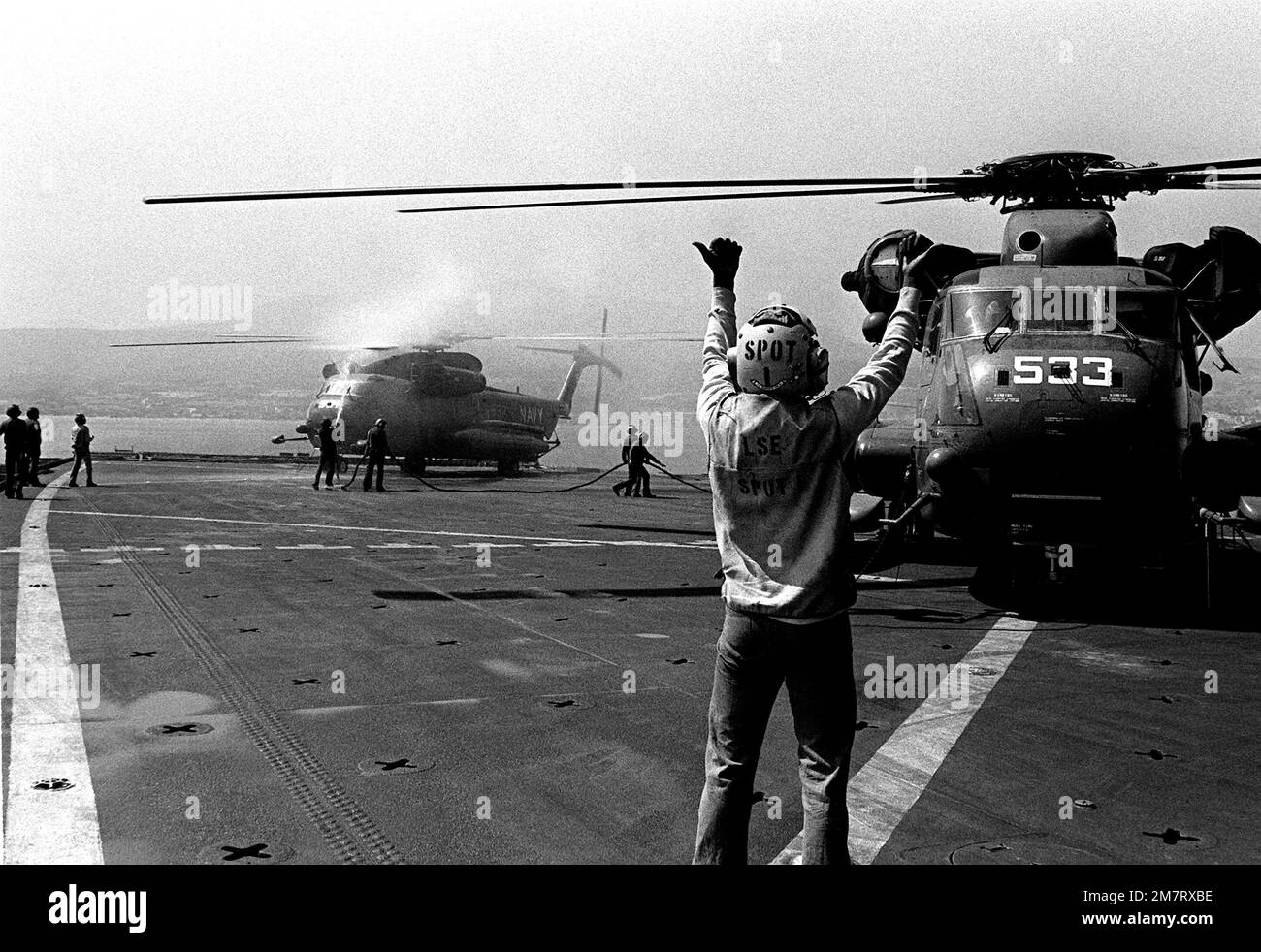 A flight deck crewman directs the pilot of a Helicopter Mine ...