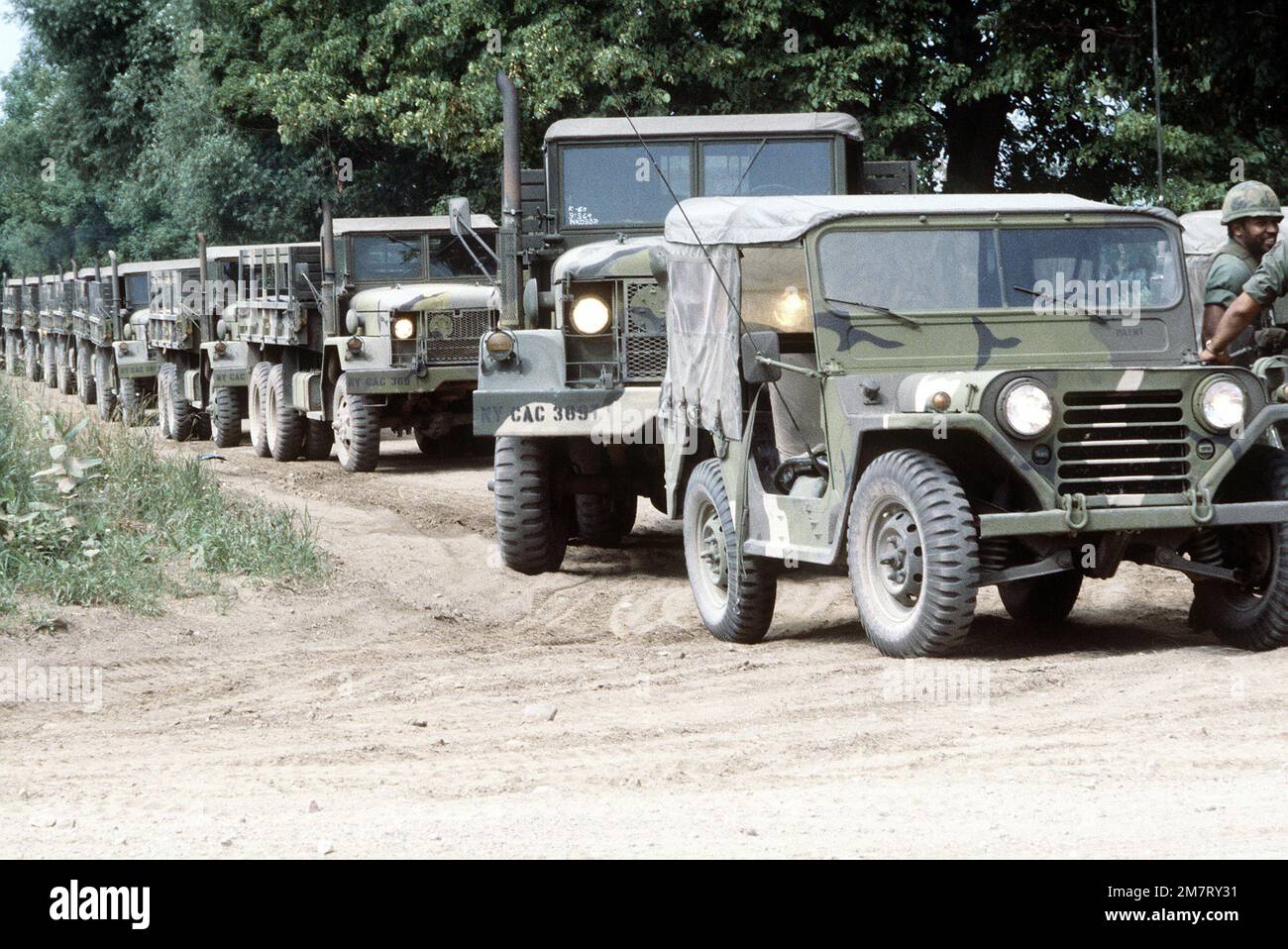 A convoy of Army trucks maneuvers through the field during exercise ...