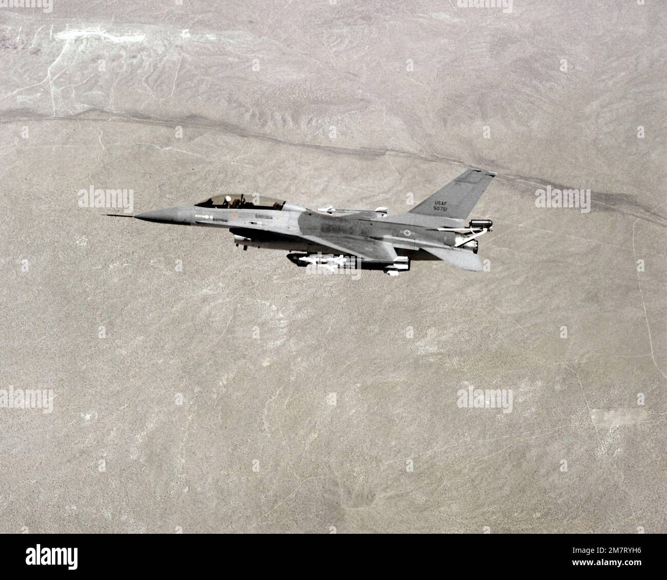 An air-to-air left side view of an F-16B Fighting Falcon aircraft with ...