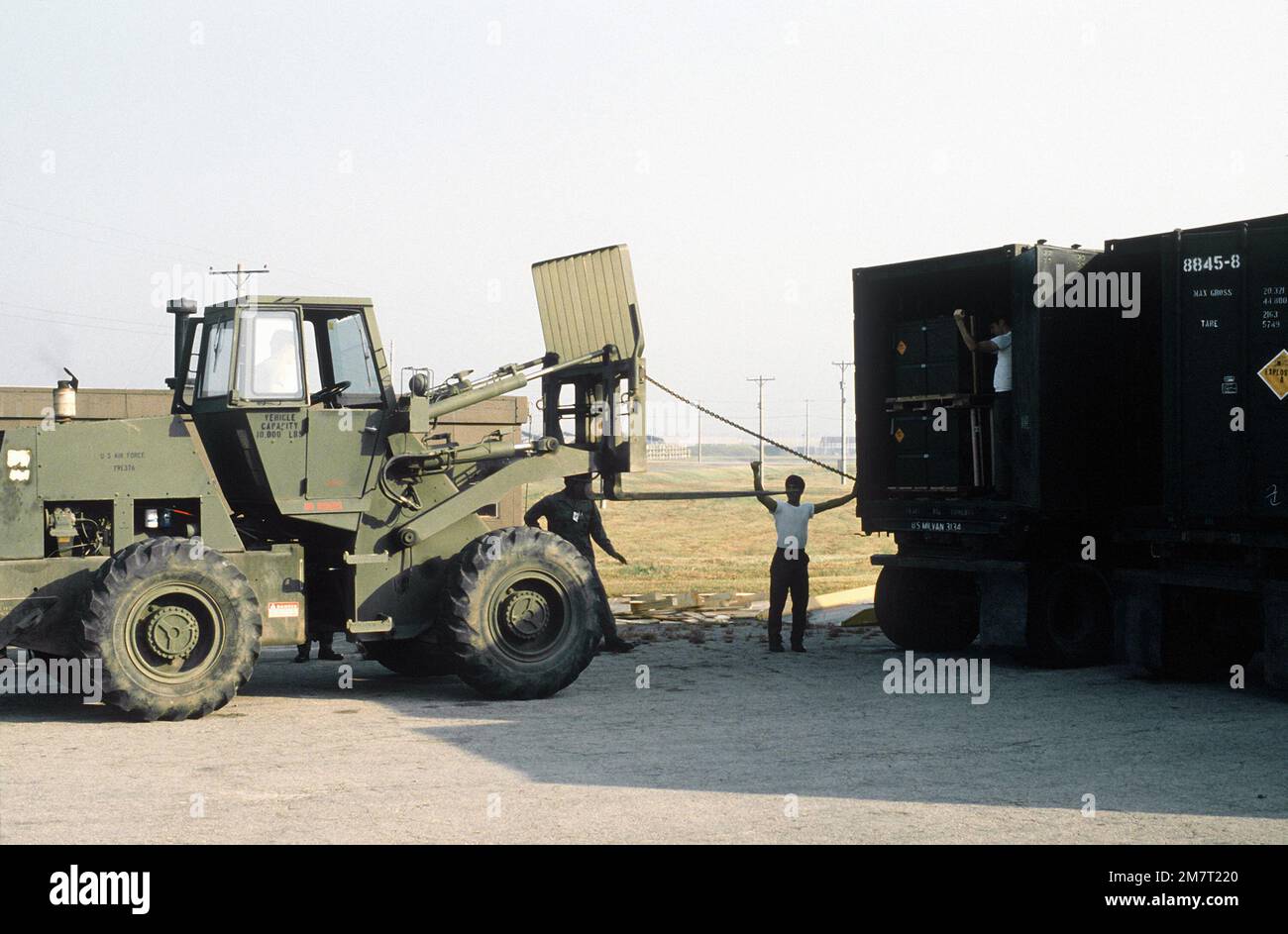 A military van is unloaded from an Army trailer, with the use of a ...