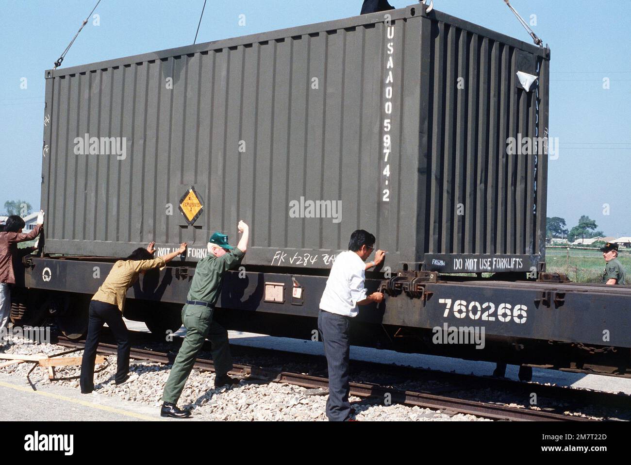 A military van is reloaded and positioned onto a flatbed railroad car ...