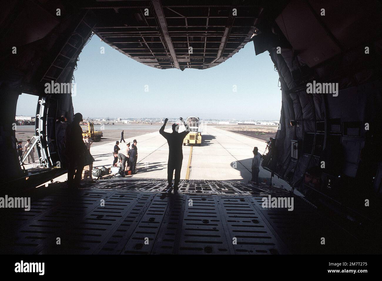 A crewman standing at the front of an Air Force C-5A Galaxy aircraft ...
