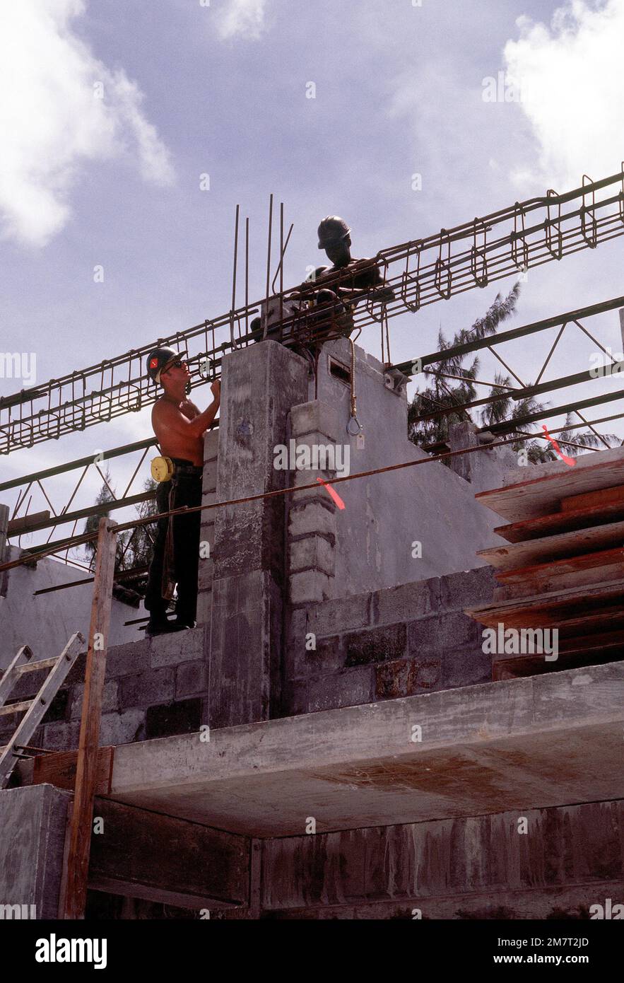 Two Seabees work on a building during construction activities. Base ...