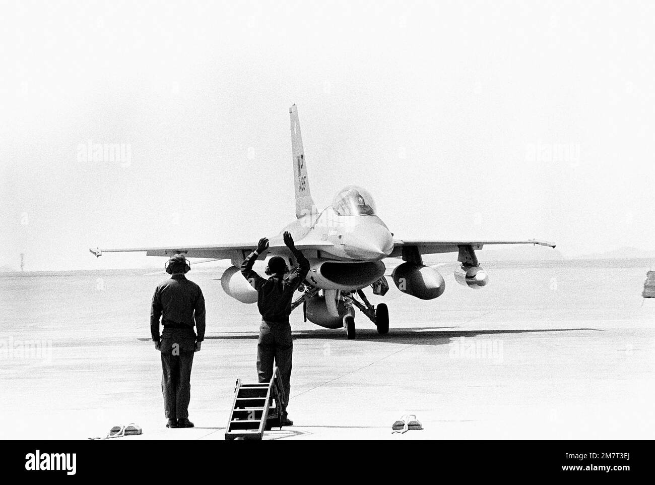 A ground crewman signals to the pilot of the first F-16 Fighting Falcon ...