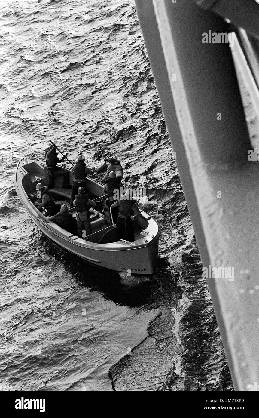 A boat is in the water beside the nuclear-powered aircraft carrier USS ...