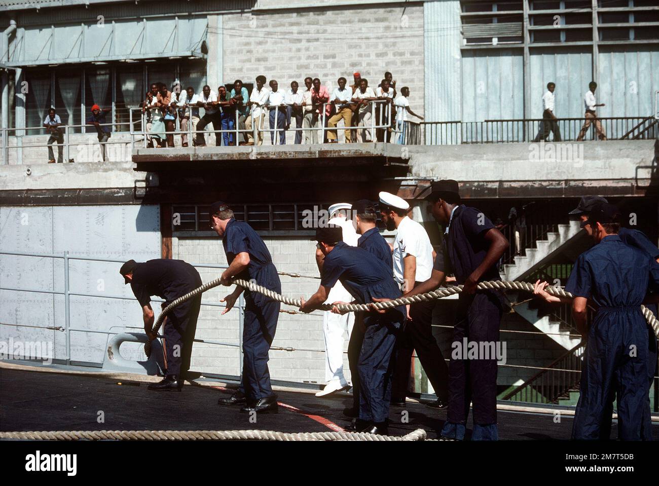 Crewman aboard the USS ARTHUR W. RADFORD (DD-968) take in the lines as ...