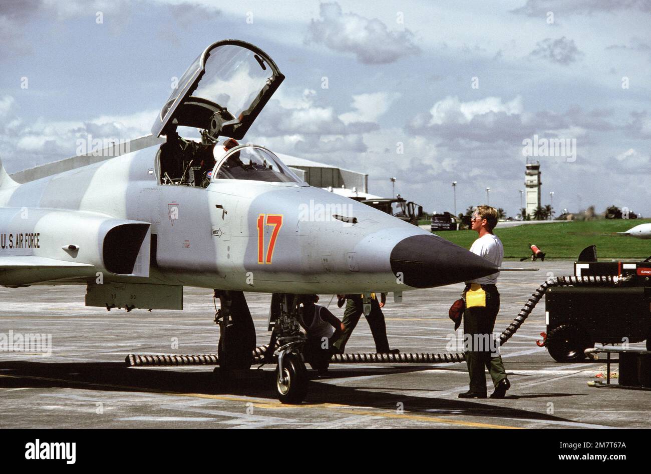 A pilot waits in the cockpit while members of the ground crew service ...
