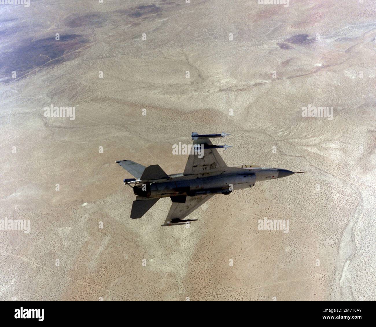 An air-to-air right underside view of an F-16B Fighting Falcon aircraft ...