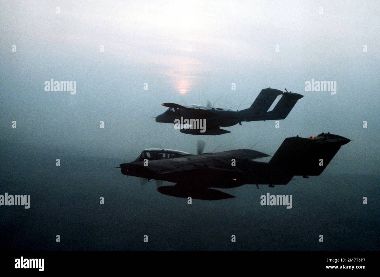 A view of two OV-10 Bronco aircraft, silhouetted against the sunset, in ...