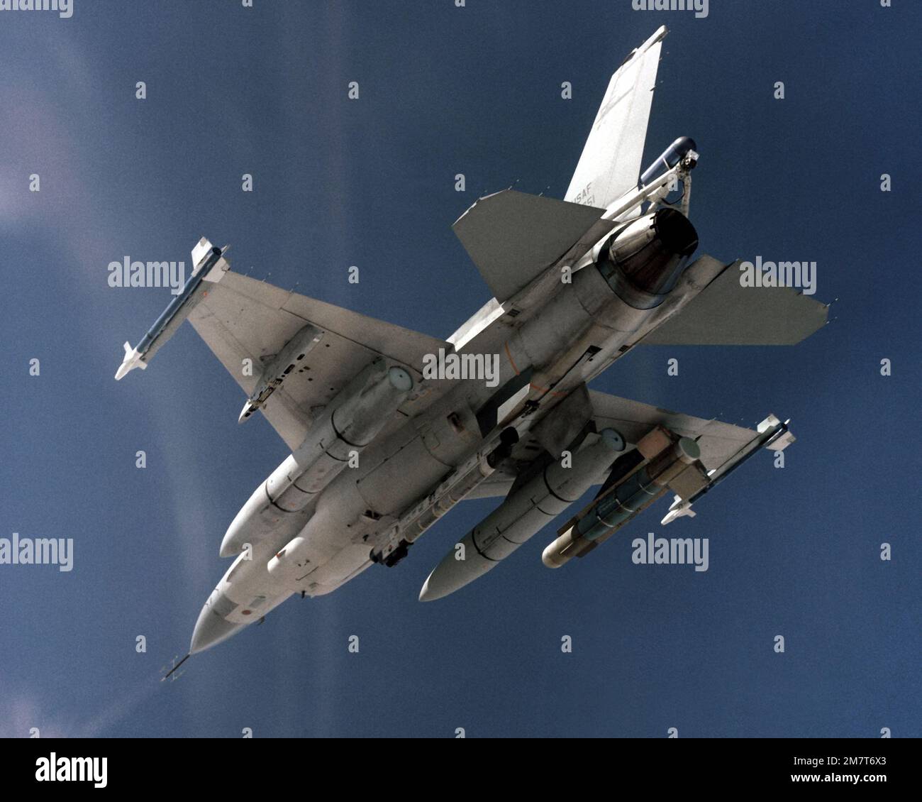 An air-to-air left underside view of an F-16B Fighting Falcon aircraft ...