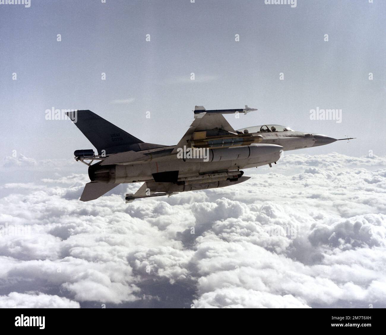 An air-to-air right side view of an F-16B Fighting Falcon aircraft with ...