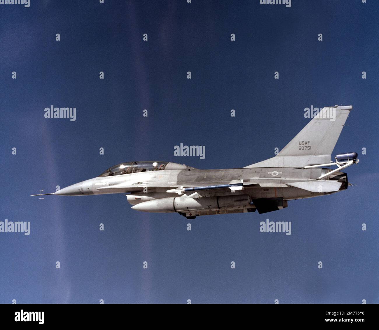 An air-to-air left side view of an F-16B Fighting Falcon aircraft with ...