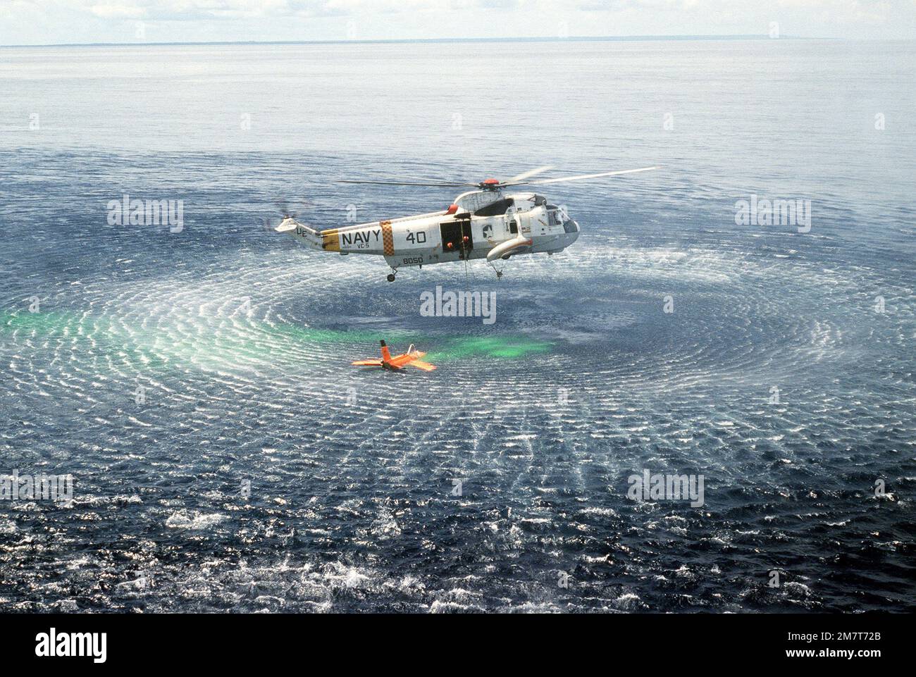 An air-to-air view of an SH-3 Sea King helicopter attaching a recovery ...