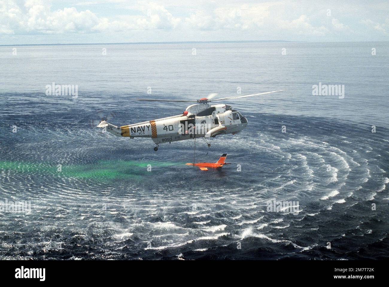 An air-to-air view of an SH-3 Sea King helicopter attaching a recovery ...