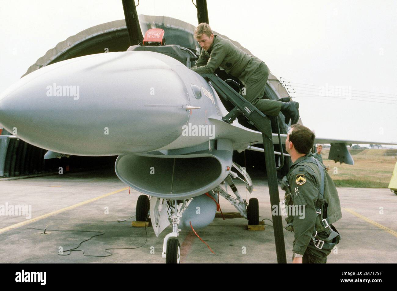 A ground crewman assists a pilot out of his F-16 Fighting Falcon ...