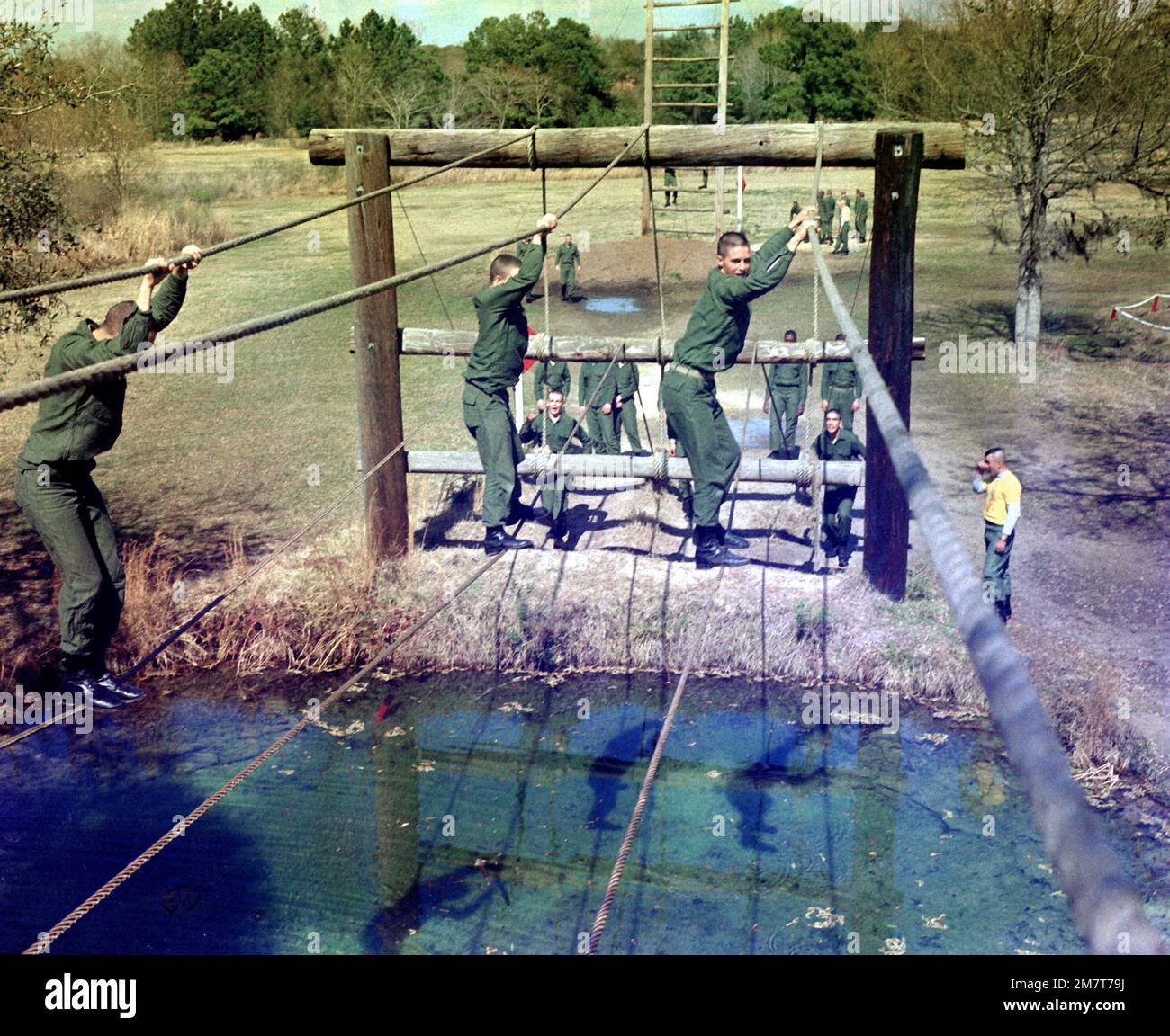 Marine recruits try to master the crossing of the monkey bridge during ...
