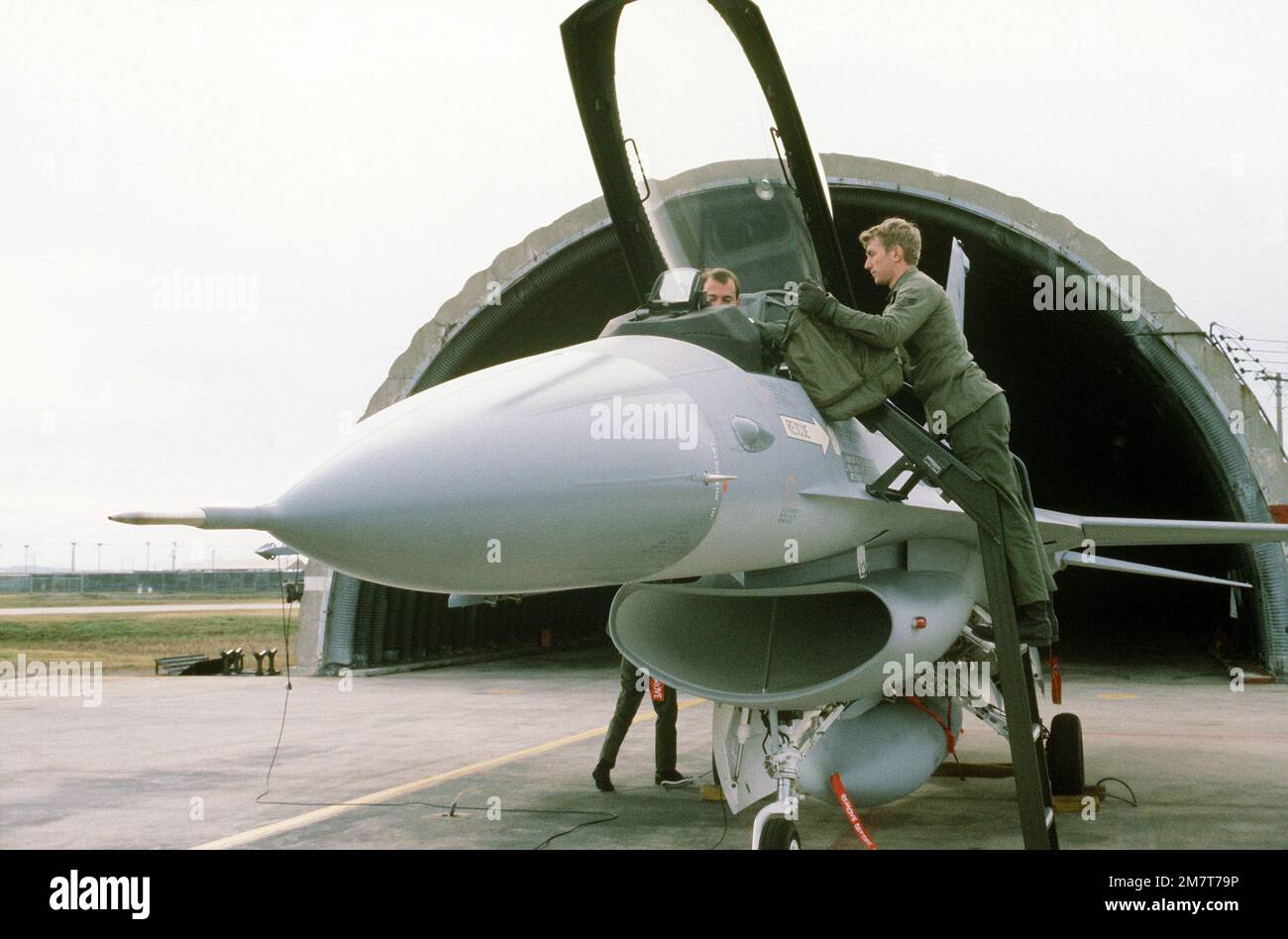 A ground crewman assists a pilot out of his F-16 Fighting Falcon ...