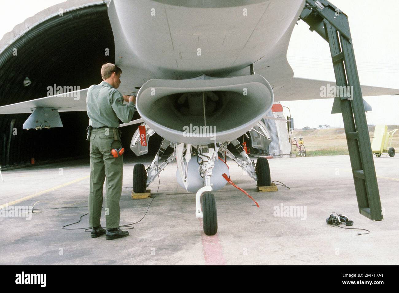 A ground crewman performs maintenance on an F-16 Fighting Falcon ...