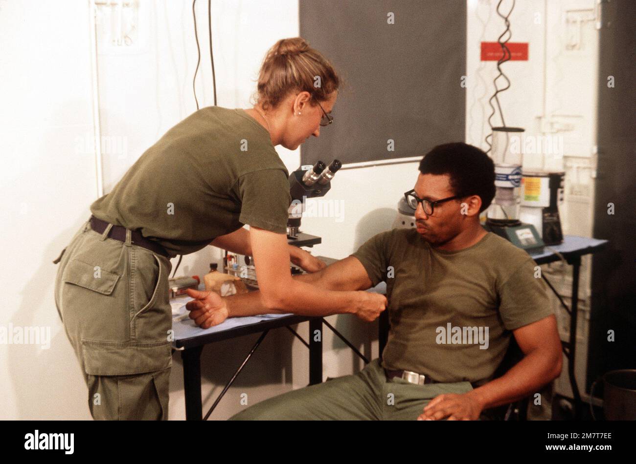 Two technicians simulate the process of drawing blood from a patient in ...