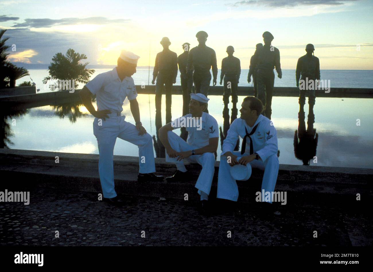 Silhouetted view as three crewmen from the salvage ship USS CONSERVER ...