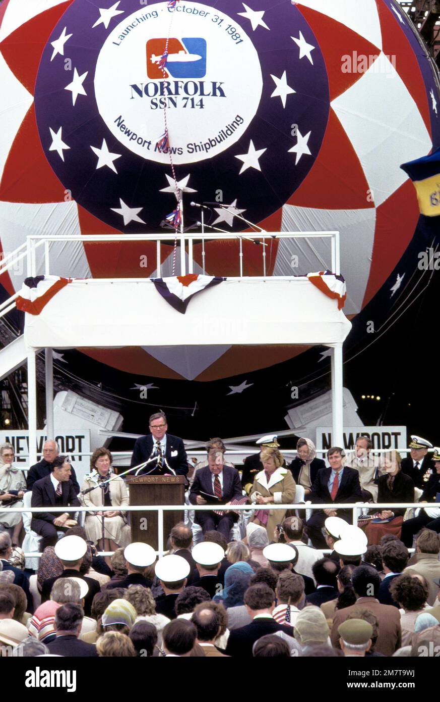 The audience and distinguished guests on the speaker's platform listen ...