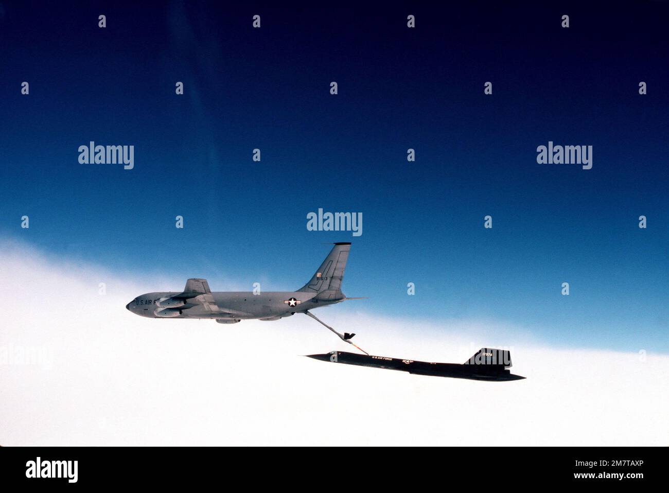 An air-to-air left side view of an SR-71A aircraft being refueled by a ...