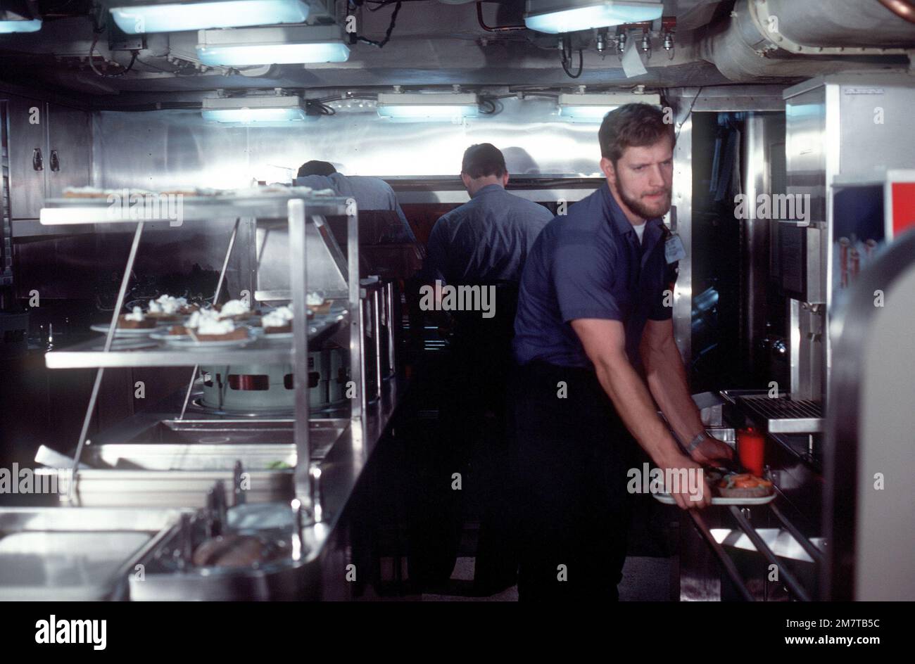 Crewmen with lunch trays in the dining hall during precommissioning ...