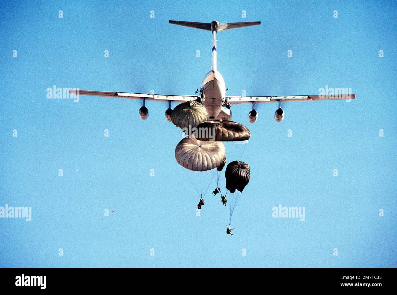 Parachutes open as troops are dropped by a C-141 Starlifter aircraft ...
