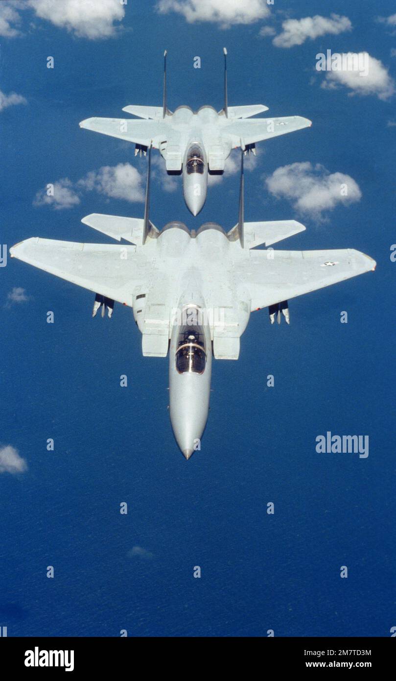 An air-to-air front view of two F-15 Eagle aircraft one directly behind ...