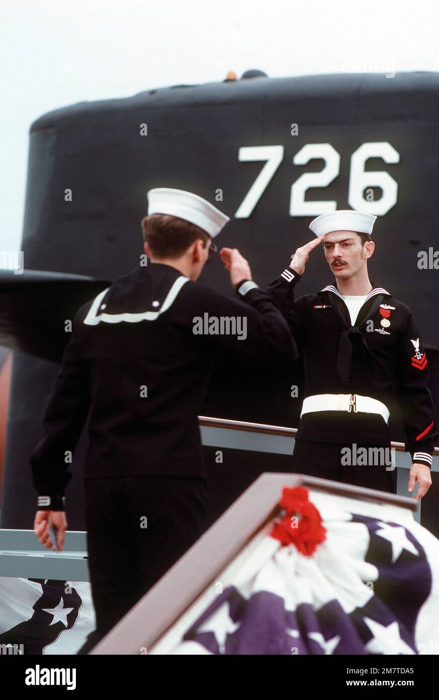 Two crewmen exchange salutes on the ramp leading to the nuclear-powered ...