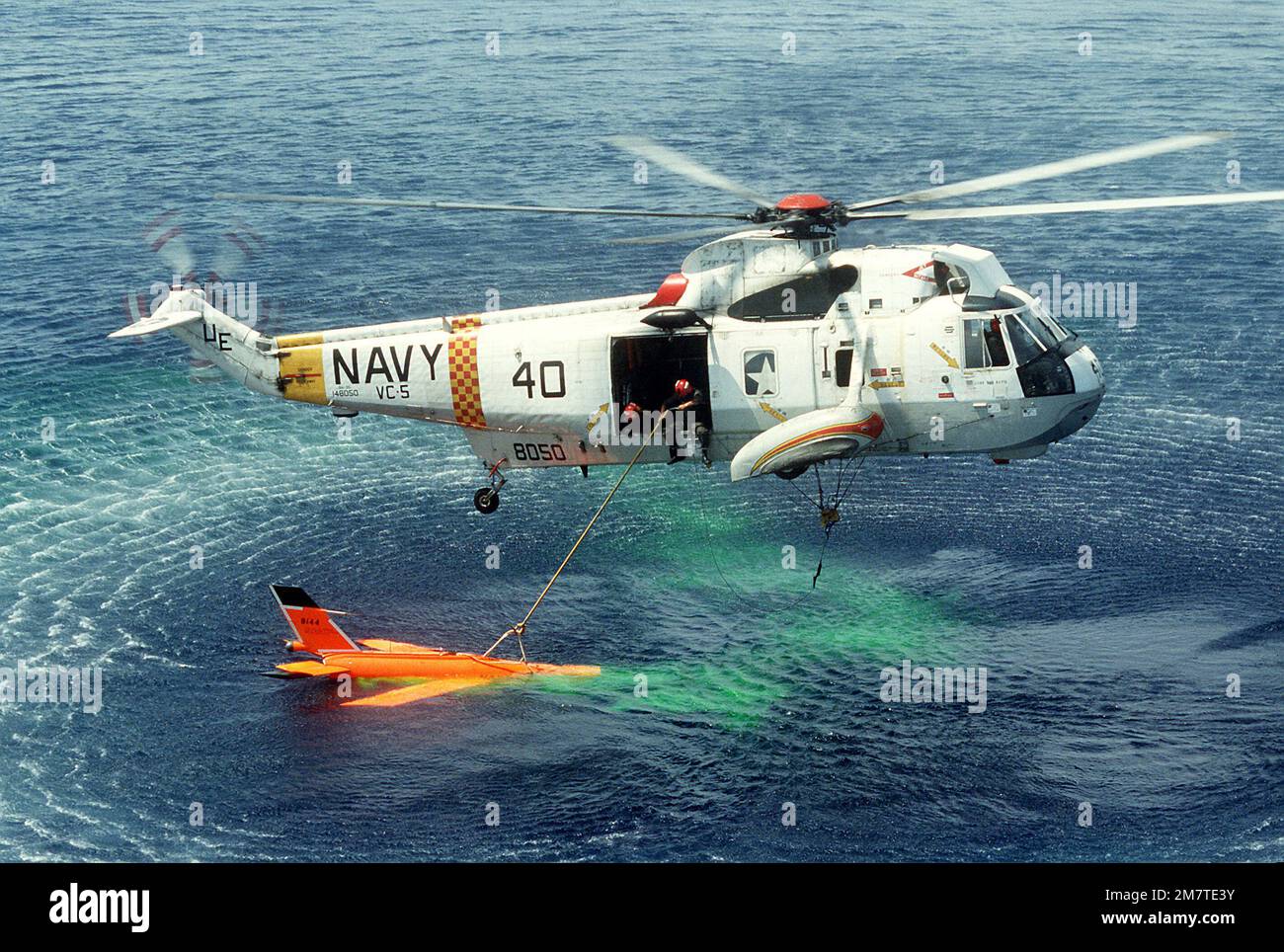 An air-to-air view of an SH-3 Sea King helicopter attaching a recovery ...