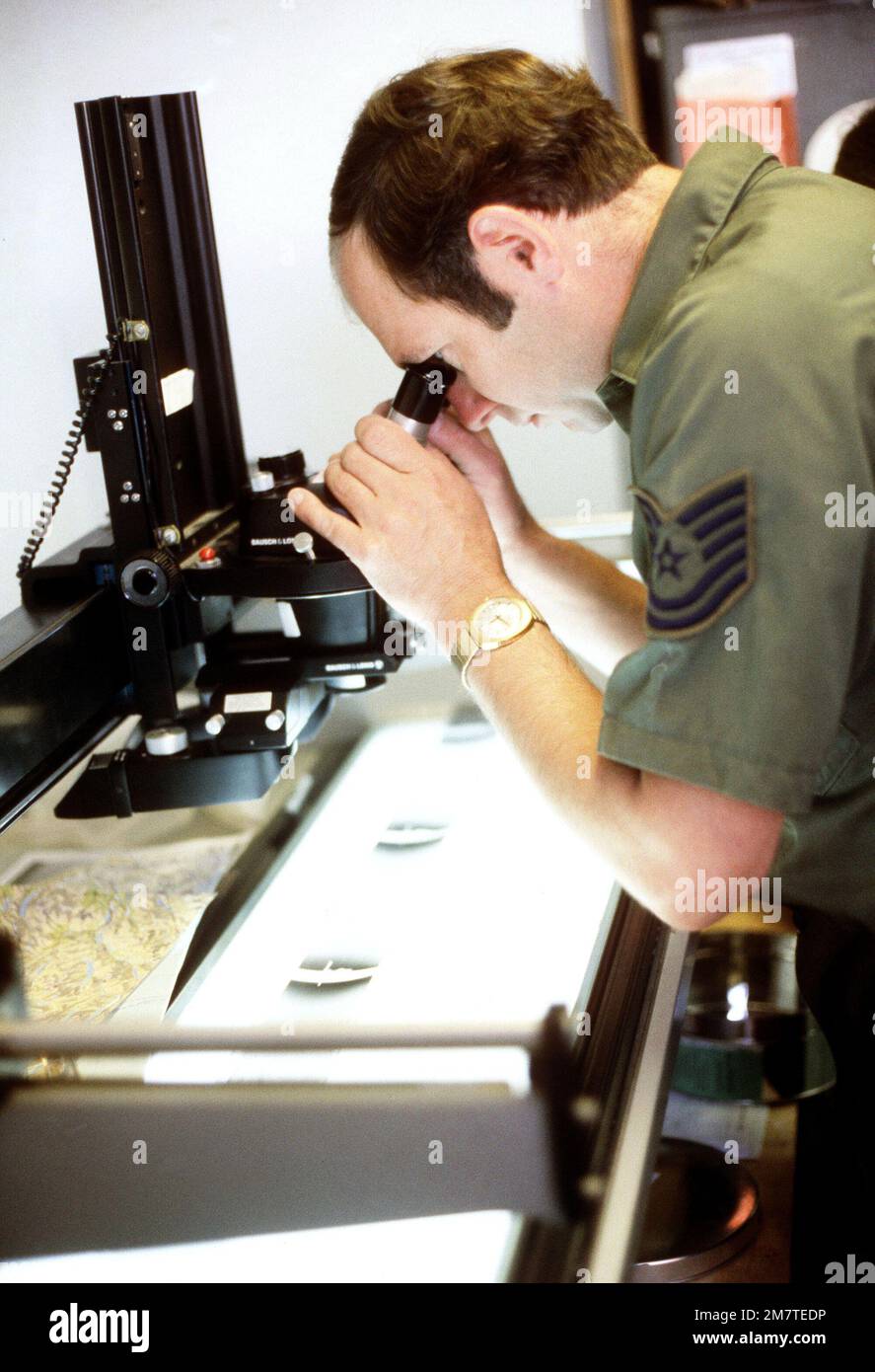 A photo interpreter uses a microscope to search film for combat data ...